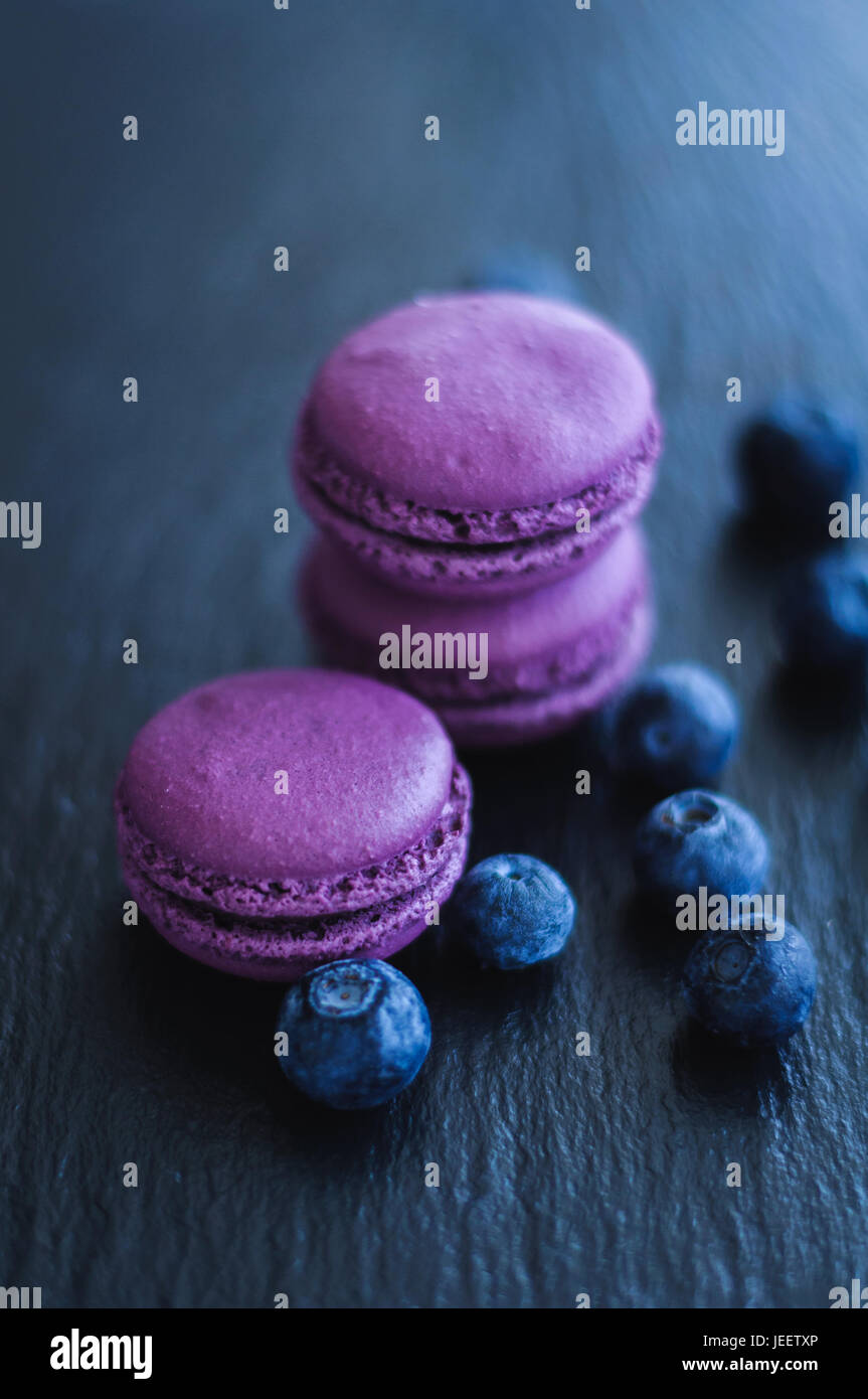 pink macaroons with blueberries on black background Stock Photo - Alamy