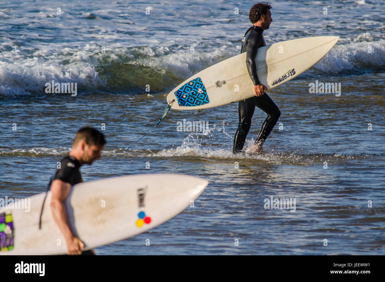 Surfers carrying surfboards, wading into the surf Stock Photo - Alamy