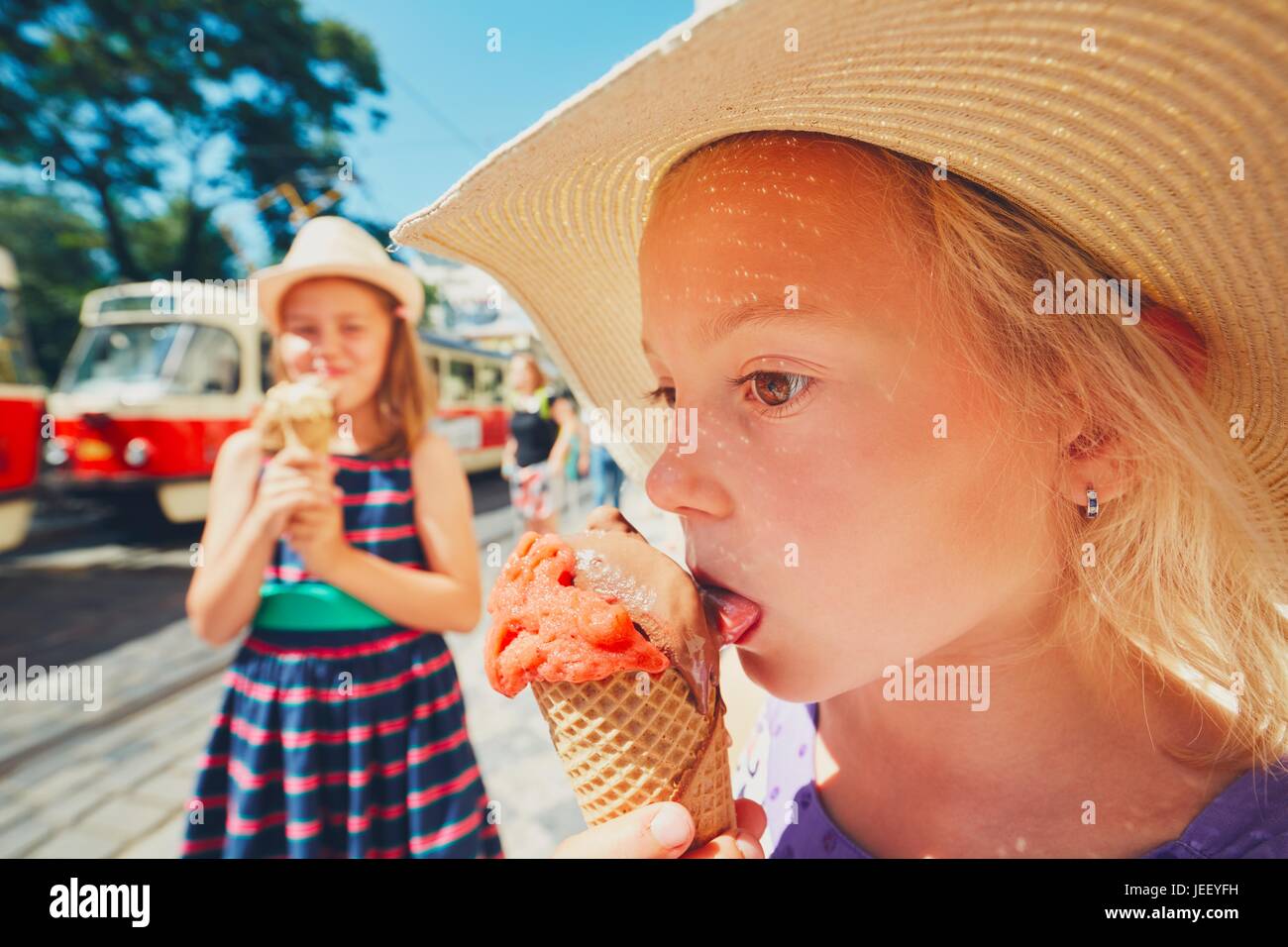 Summer day in the city. Cute little girls with hats eating big ice ...
