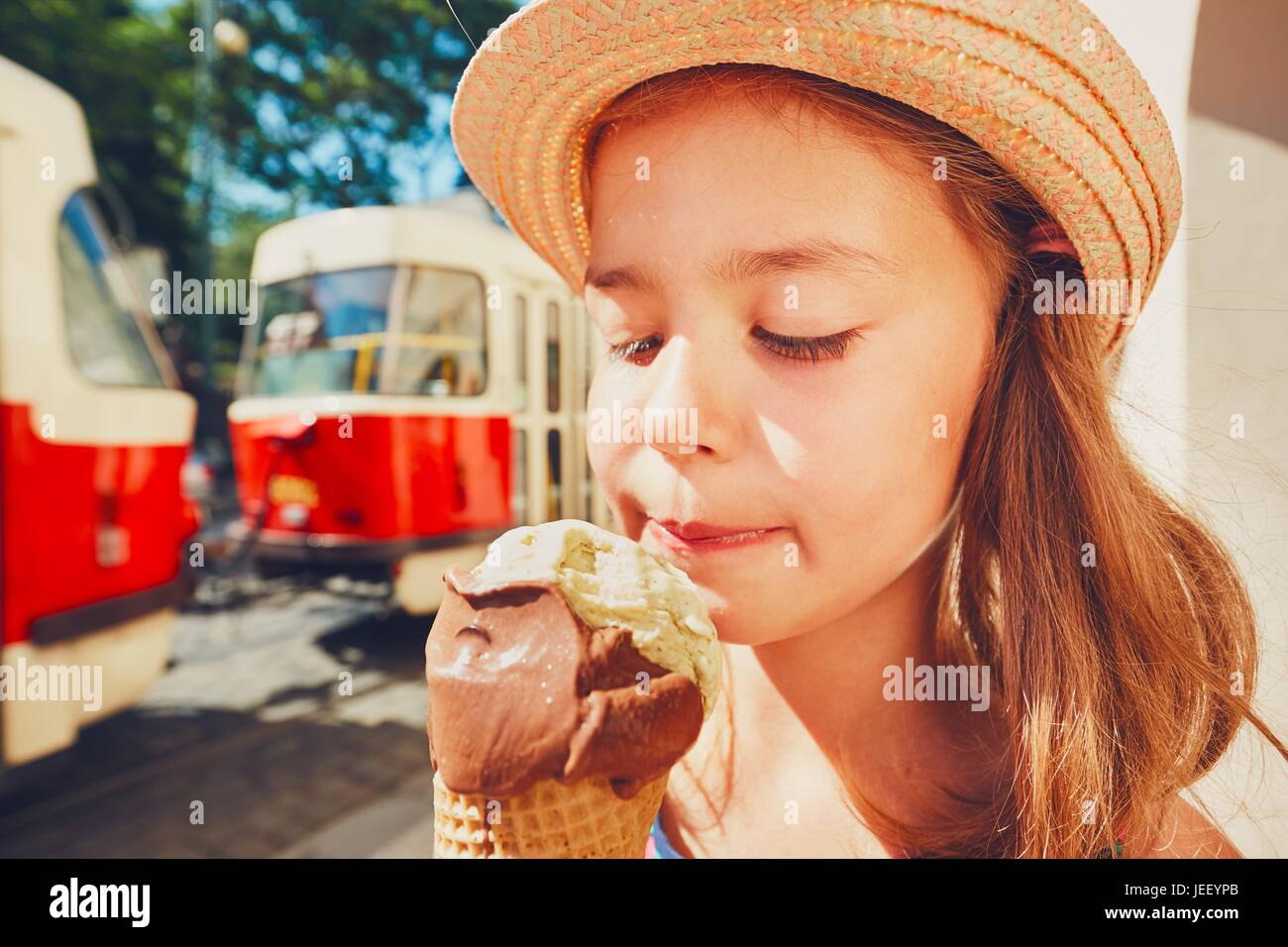 Summer day in the city. Cute little girl with hat eating big ice cream ...