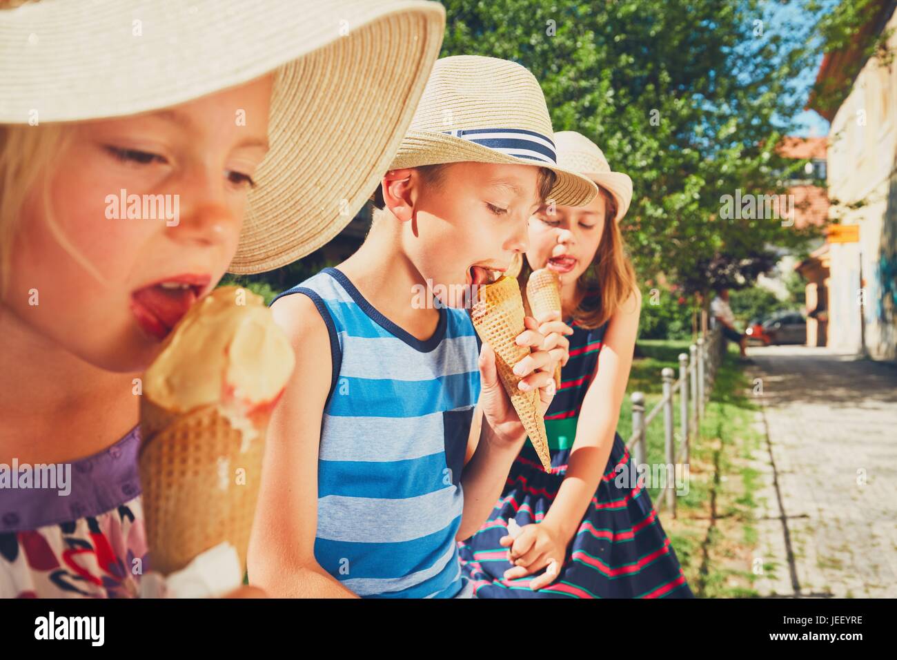 Summer day in the city. Cute siblings with hats eating big ice cream in ...