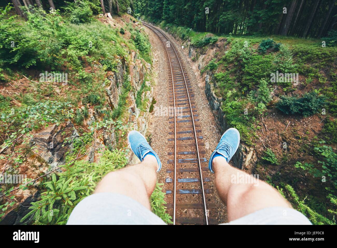 Man sitting above railroad track in the middle of the deep forest. Ore ...