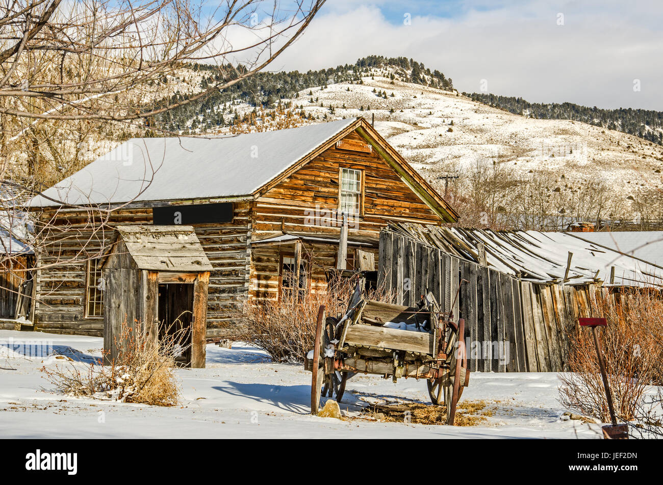 Log home, outhouse, and a wagon on a winter day in a ghost town with a ...