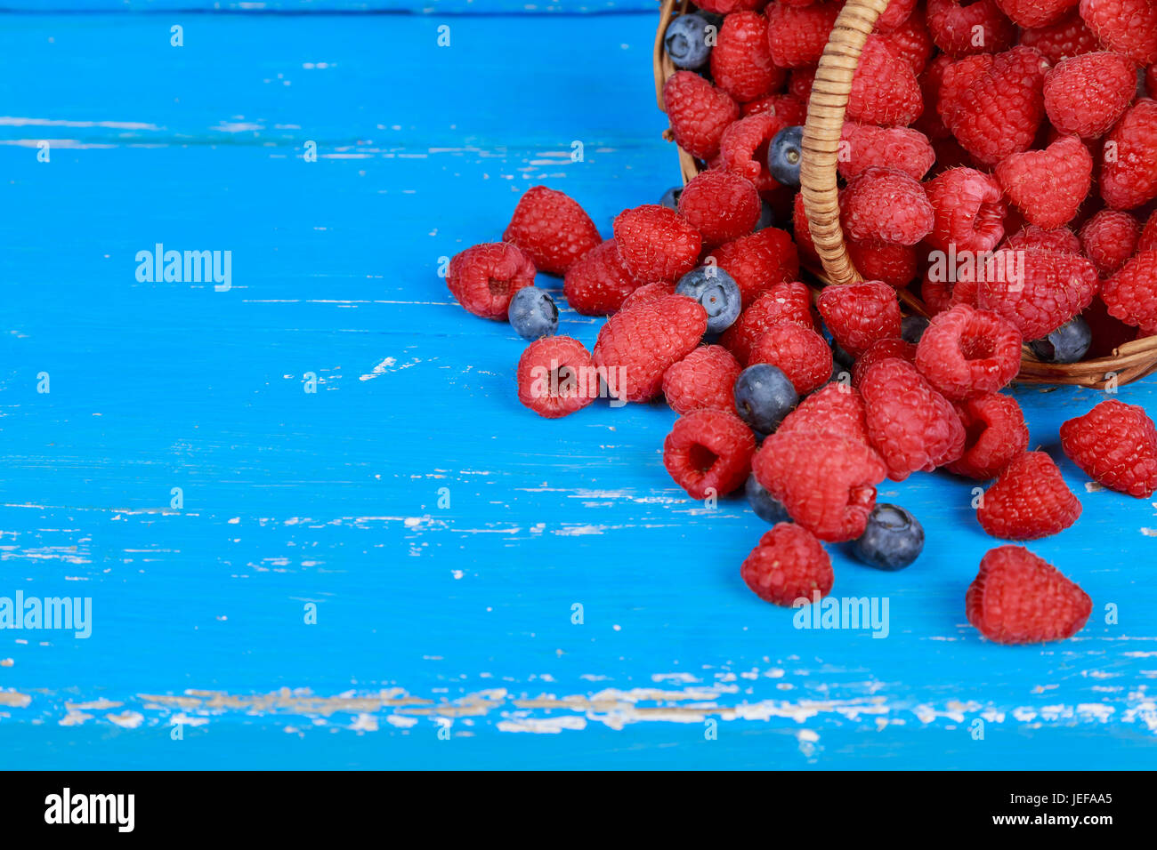 Fresh berry fruit pile basket with leaves placed on old wooden planks ...