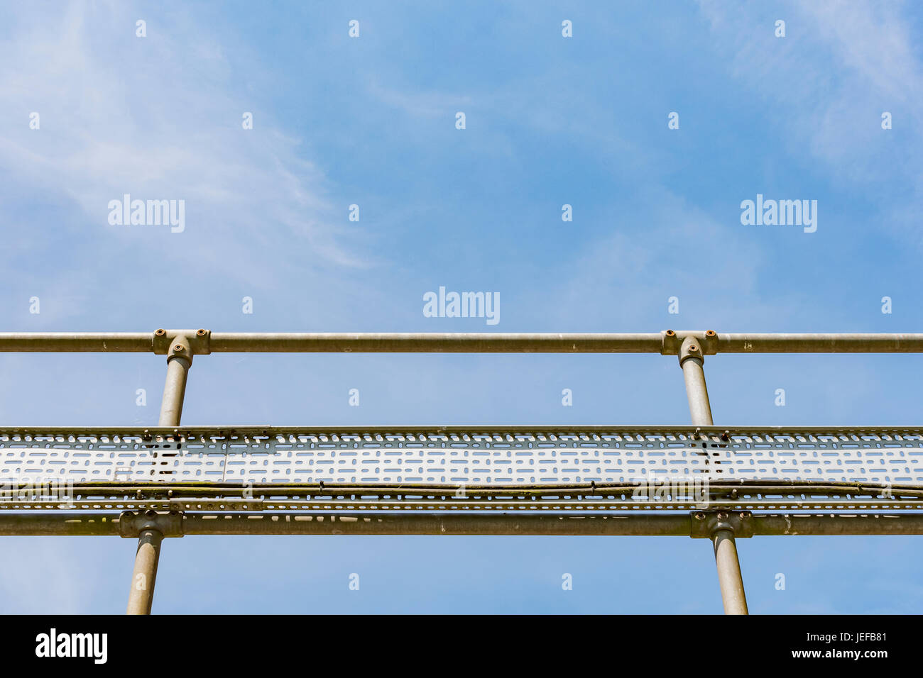 Industrial handrail [and electrical cabling] seen against blue summer ...
