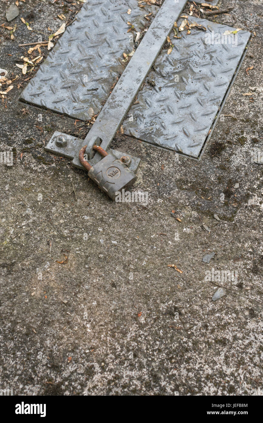 Locked padlock blocking access to manhole cover. Metaphor locked in ...
