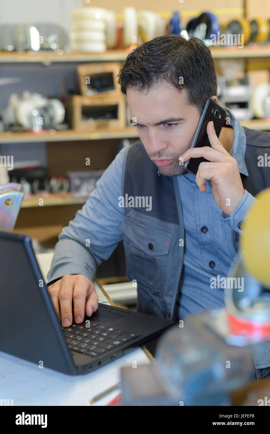warehouse manager using telephone and laptop at desk in warehouse Stock ...