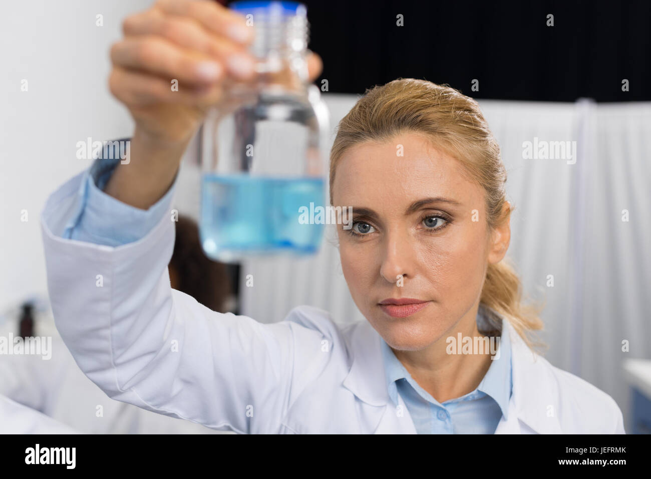 Female Scientist Examine Flask With Blue Luquid Working In Modern ...