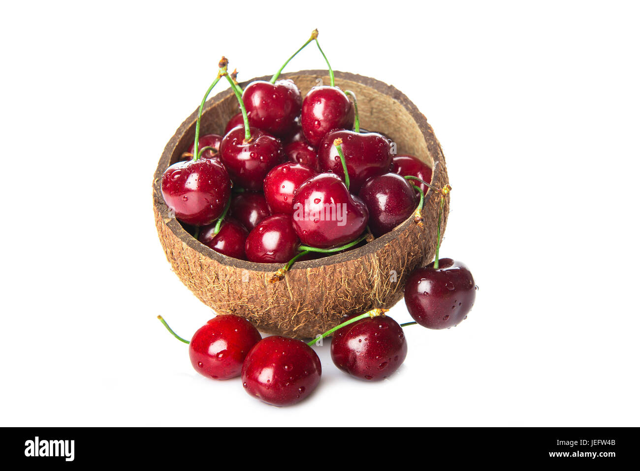 Coconut shell full of fresh cherries isolated on a white background ...