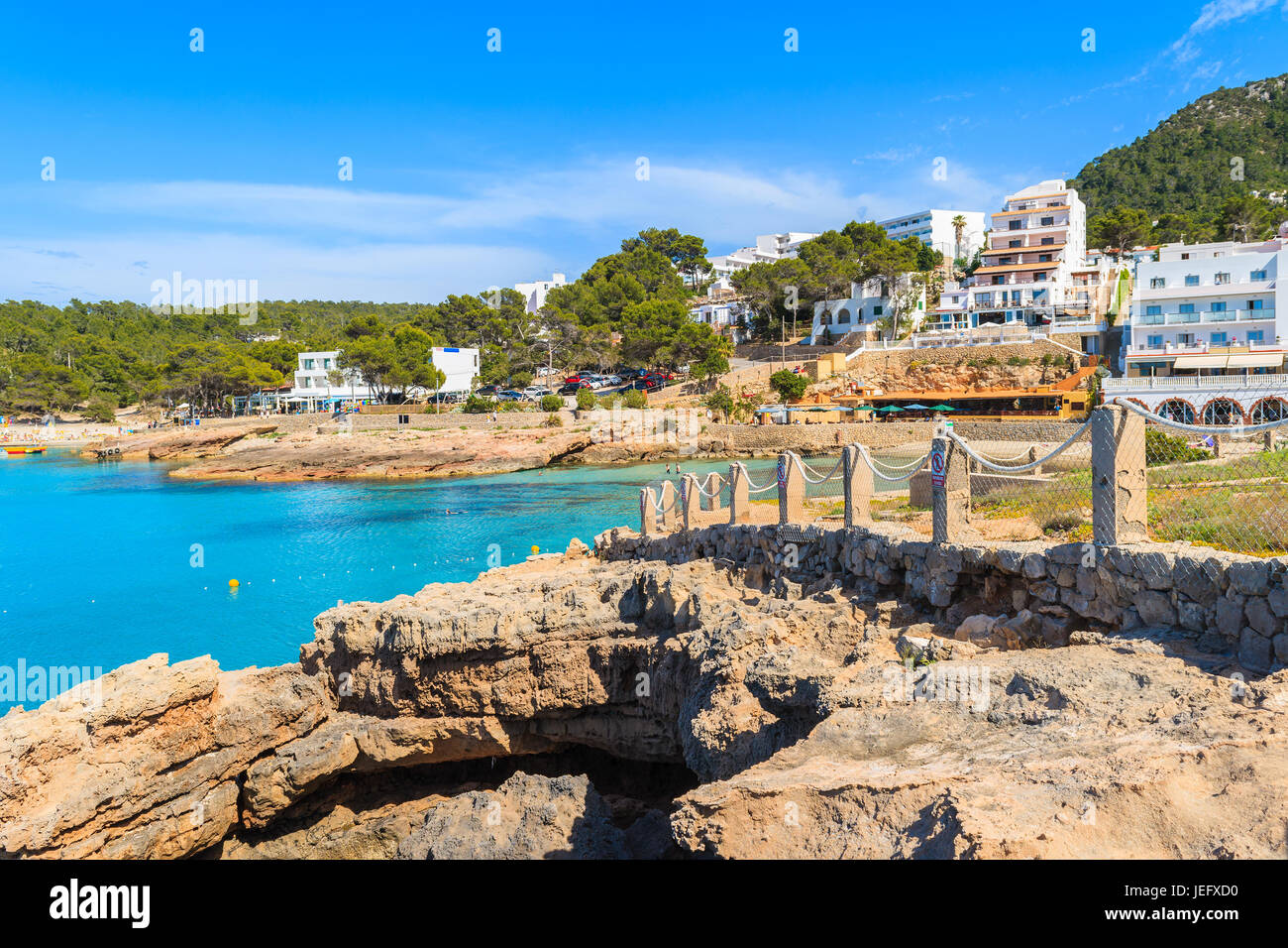 Rocks on coast of Cala Portinatx bay with hotels and restaurants in ...