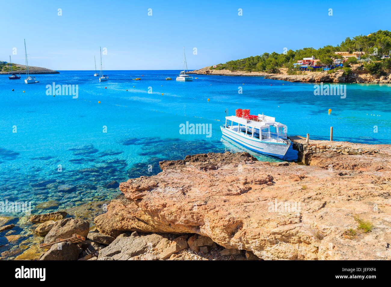 White and blue colour ferry boat for tourists mooring in Cala Portinatx ...