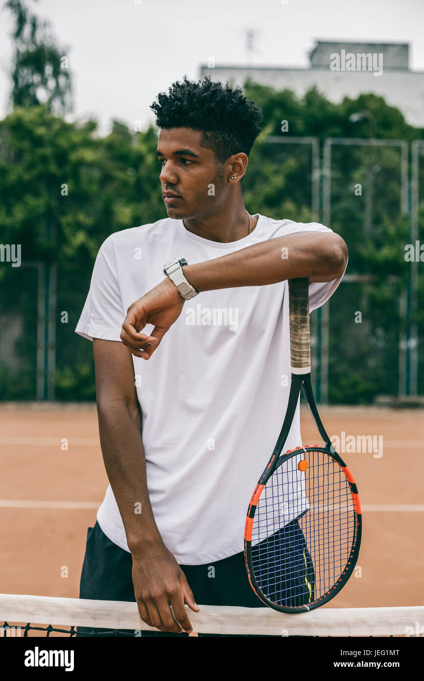 Concentrated young man holds his hand on a tennis racket Stock Photo ...
