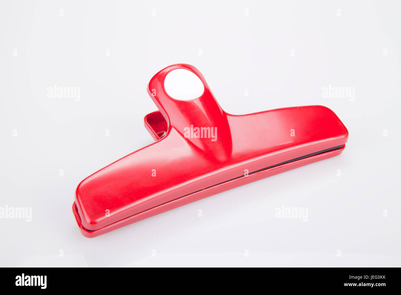 Red plastic chips bag clip on a white surface. Bag clip isolated on ...