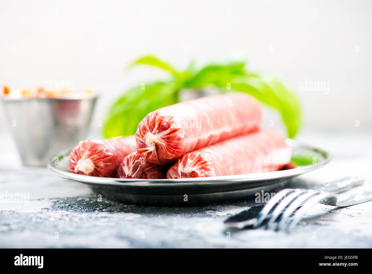 raw sausages on metal plate and on a table Stock Photo - Alamy