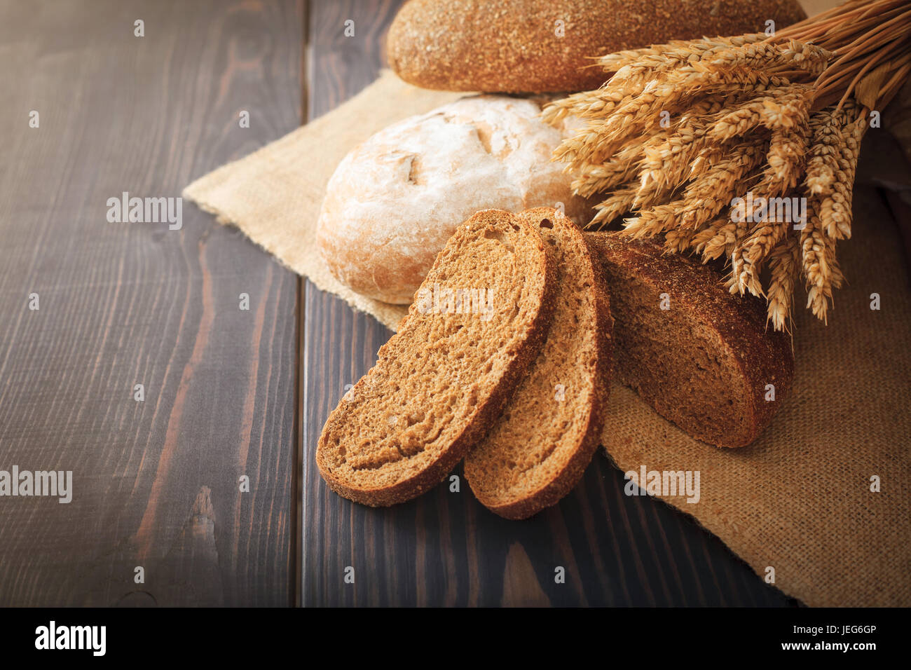 Fresh bread and wheat on the dark wooden table Stock Photo - Alamy