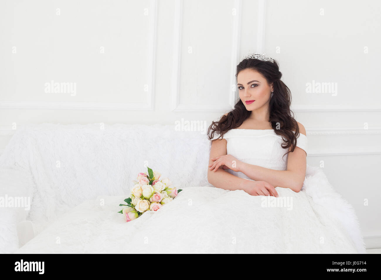 bride in wedding dress sitting on a sofa wedding bouquet Stock Photo ...