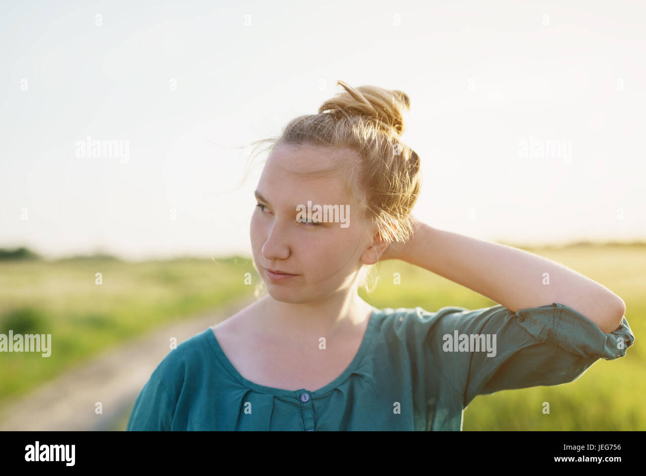 teen girl standing on dirt rural road between fields, closeup portrait ...