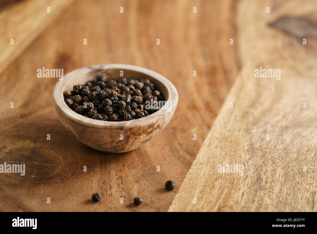 black dry pepper in wooden bowl on table, with copy space Stock Photo ...