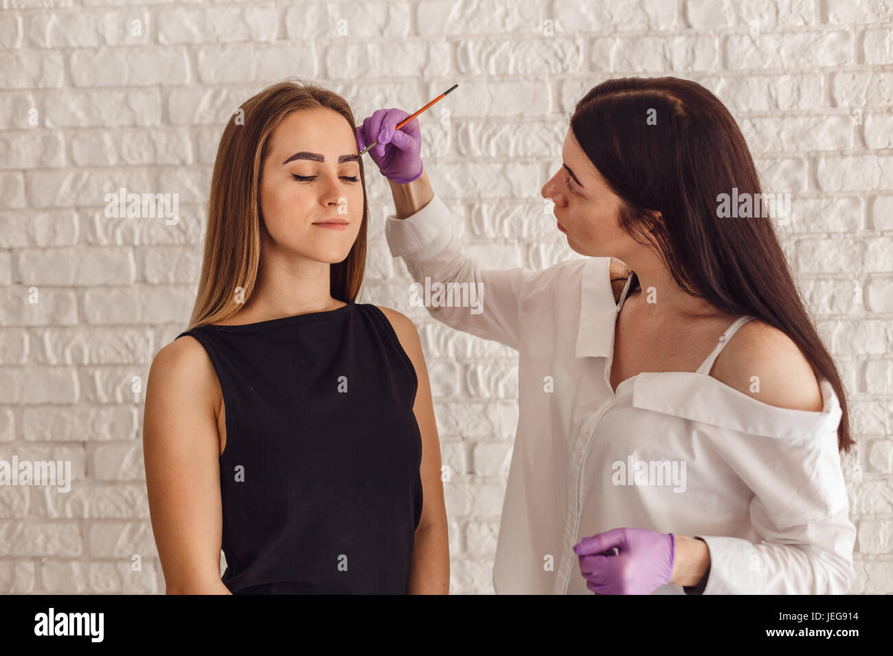 Master cosmetologist painted on eyebrows female customer in beauty ...