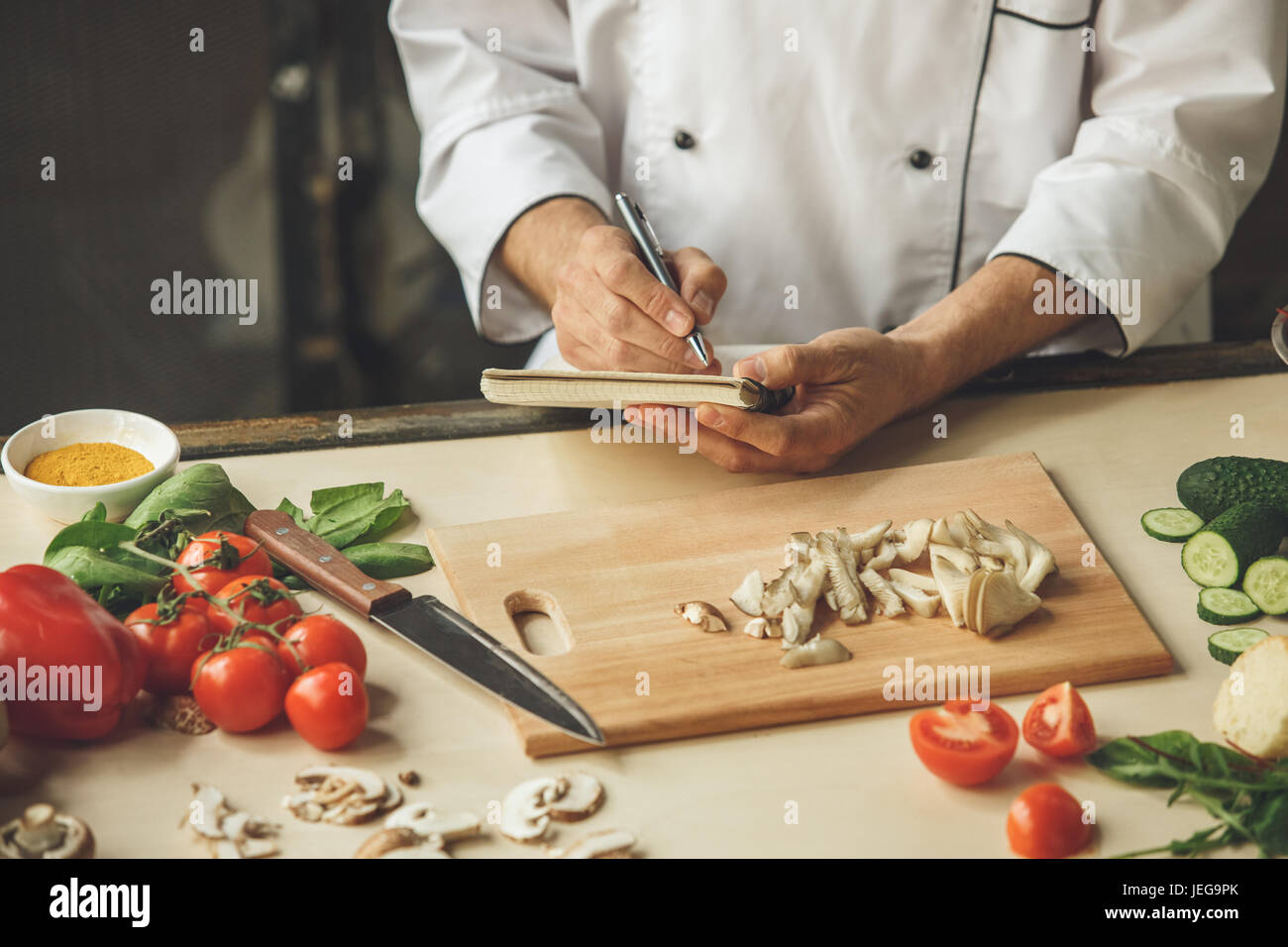 Mature male professional chef cooking meal indoors writing receipt ...