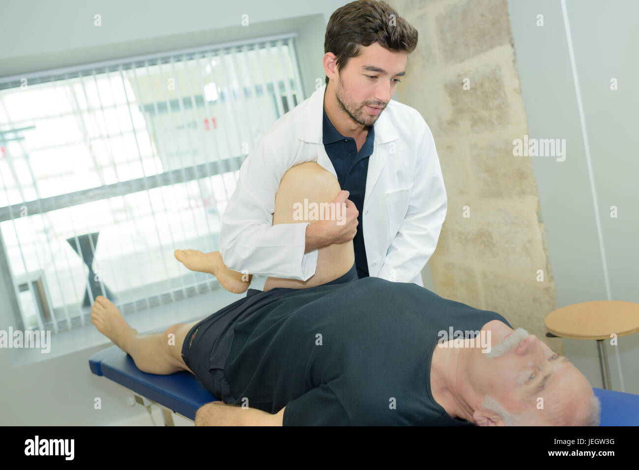doctor is stretching mans leg on physiotherapy session Stock Photo - Alamy