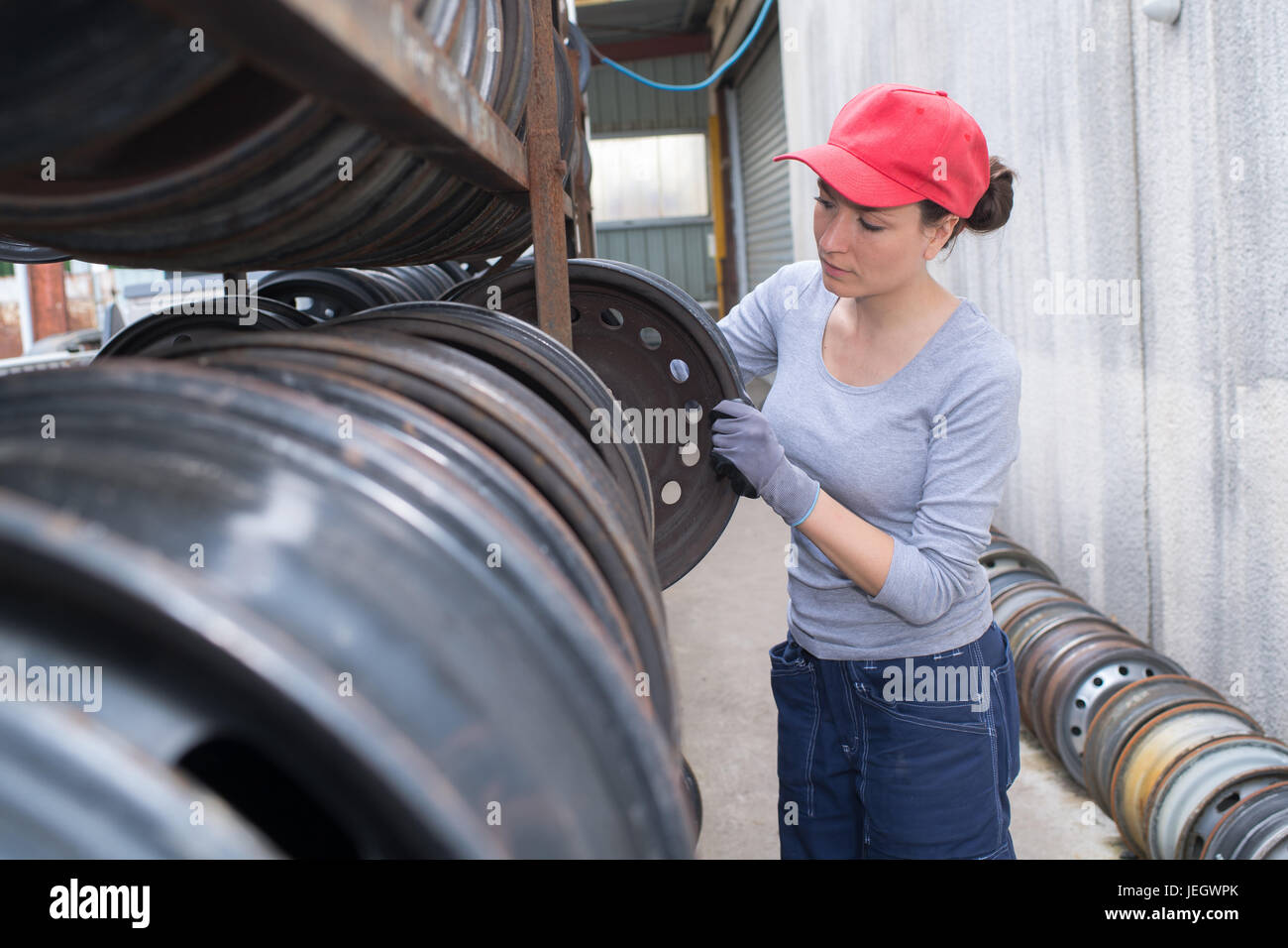 Woman taking wheel rim from racking Stock Photo - Alamy