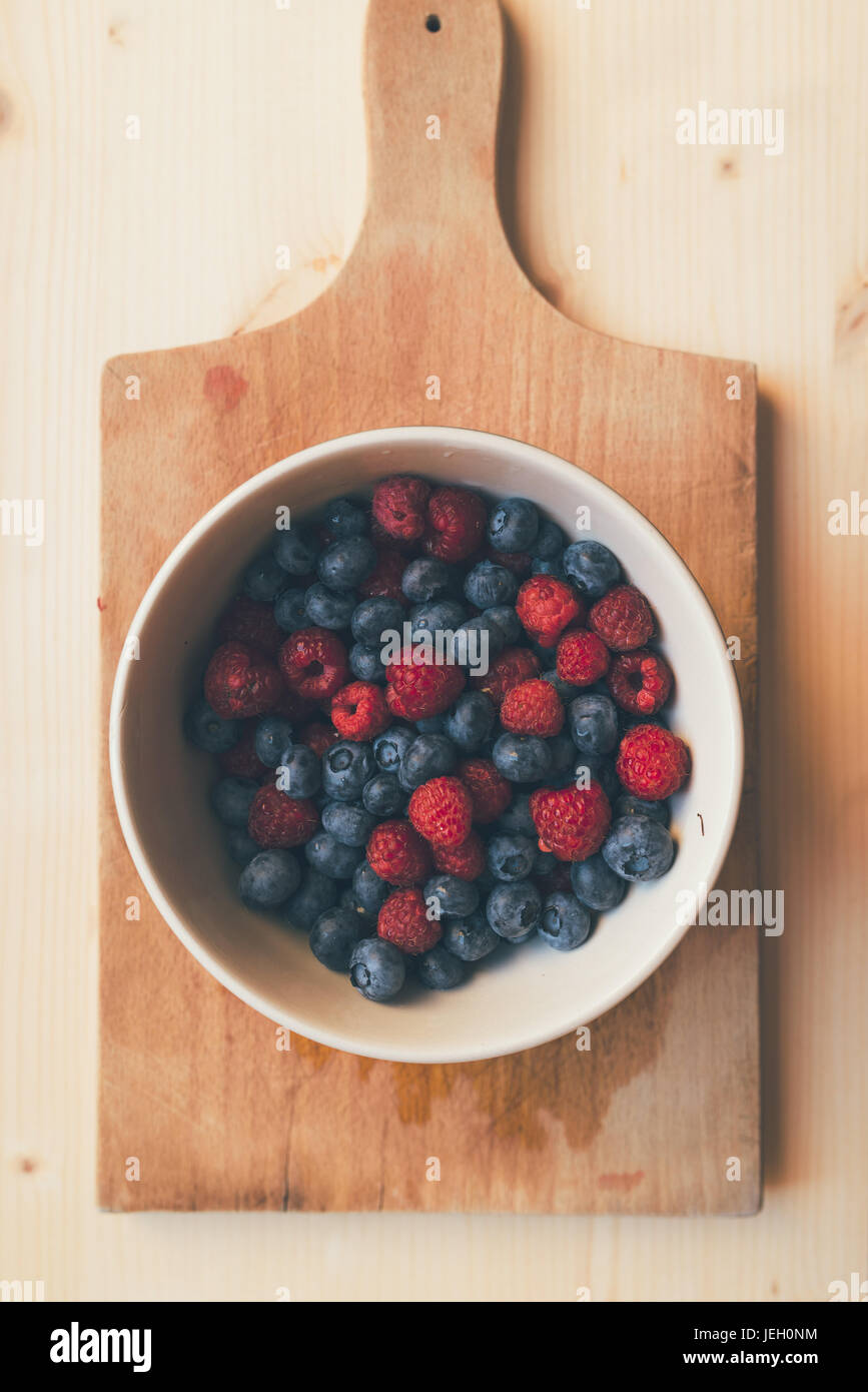 Raspberries and blueberries in bowl, top view Stock Photo - Alamy