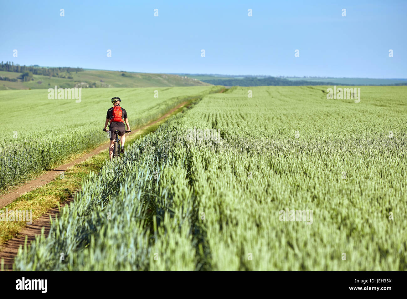 Rear view of the young cyclist with backpack cycling in the track of ...