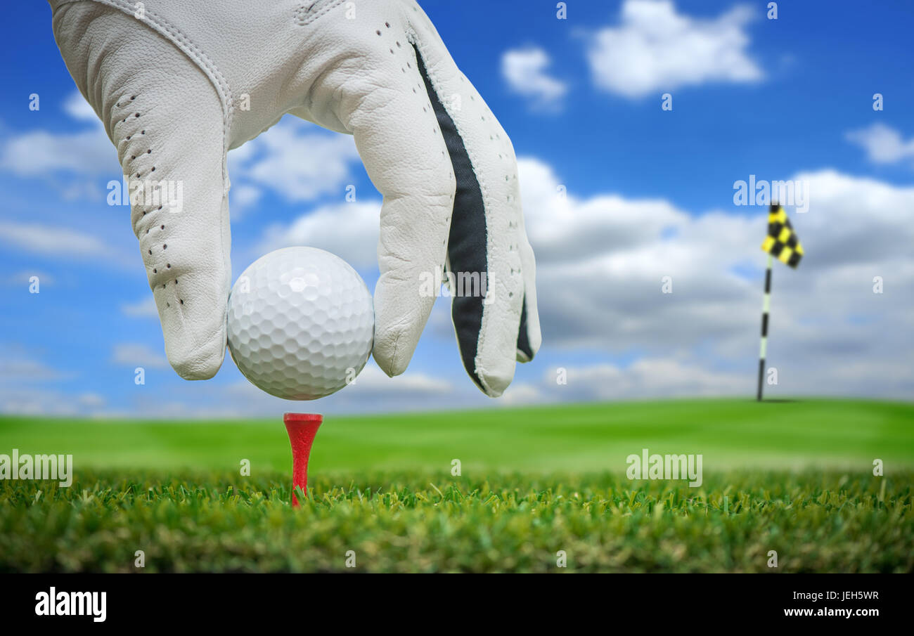 golf players hand placing ball on tee with blue sky Stock Photo - Alamy