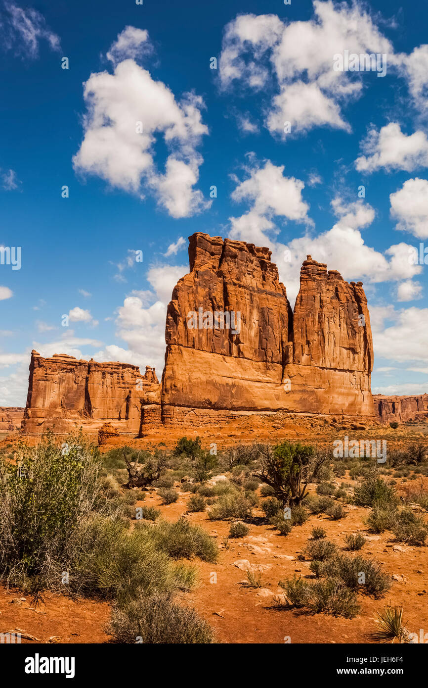 A rugged rock formation in the desert under blue sky with cloud ...