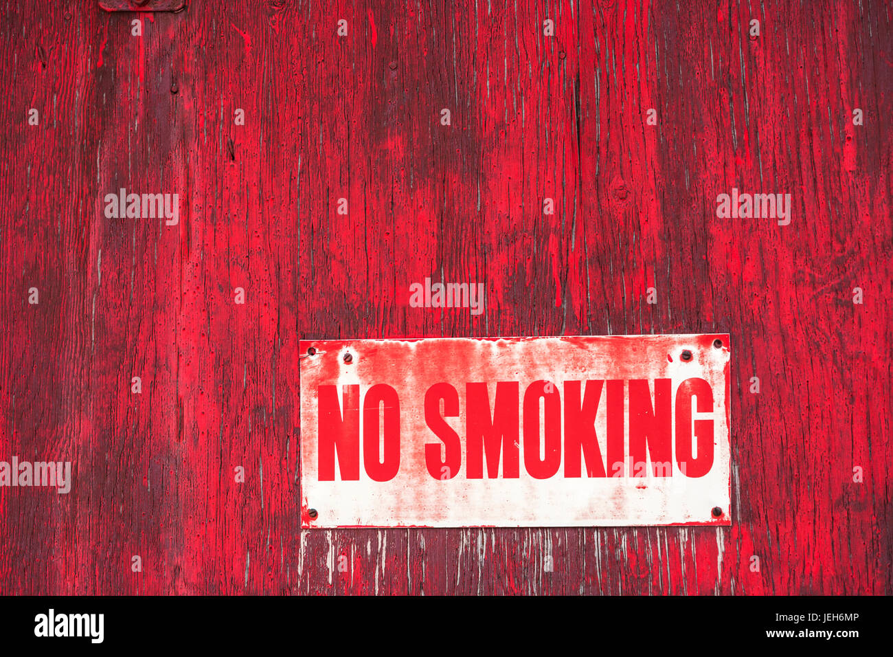 A no smoking sign on a painted red wooden wall; Orion, Alberta, Canada ...