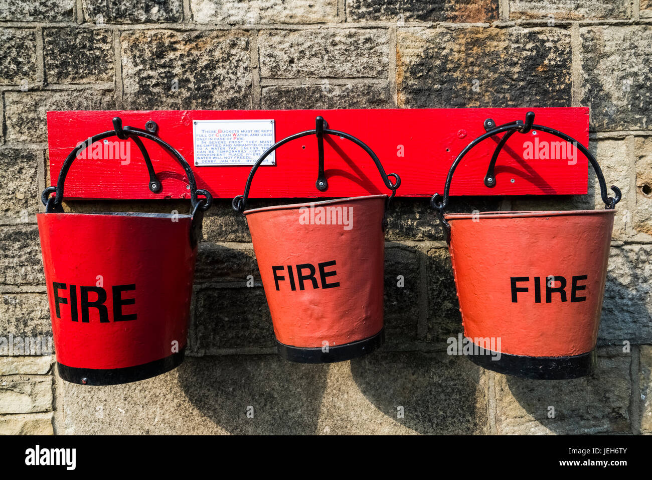 Three red pails labeled fire hanging on a wall; Yorkshire, England ...