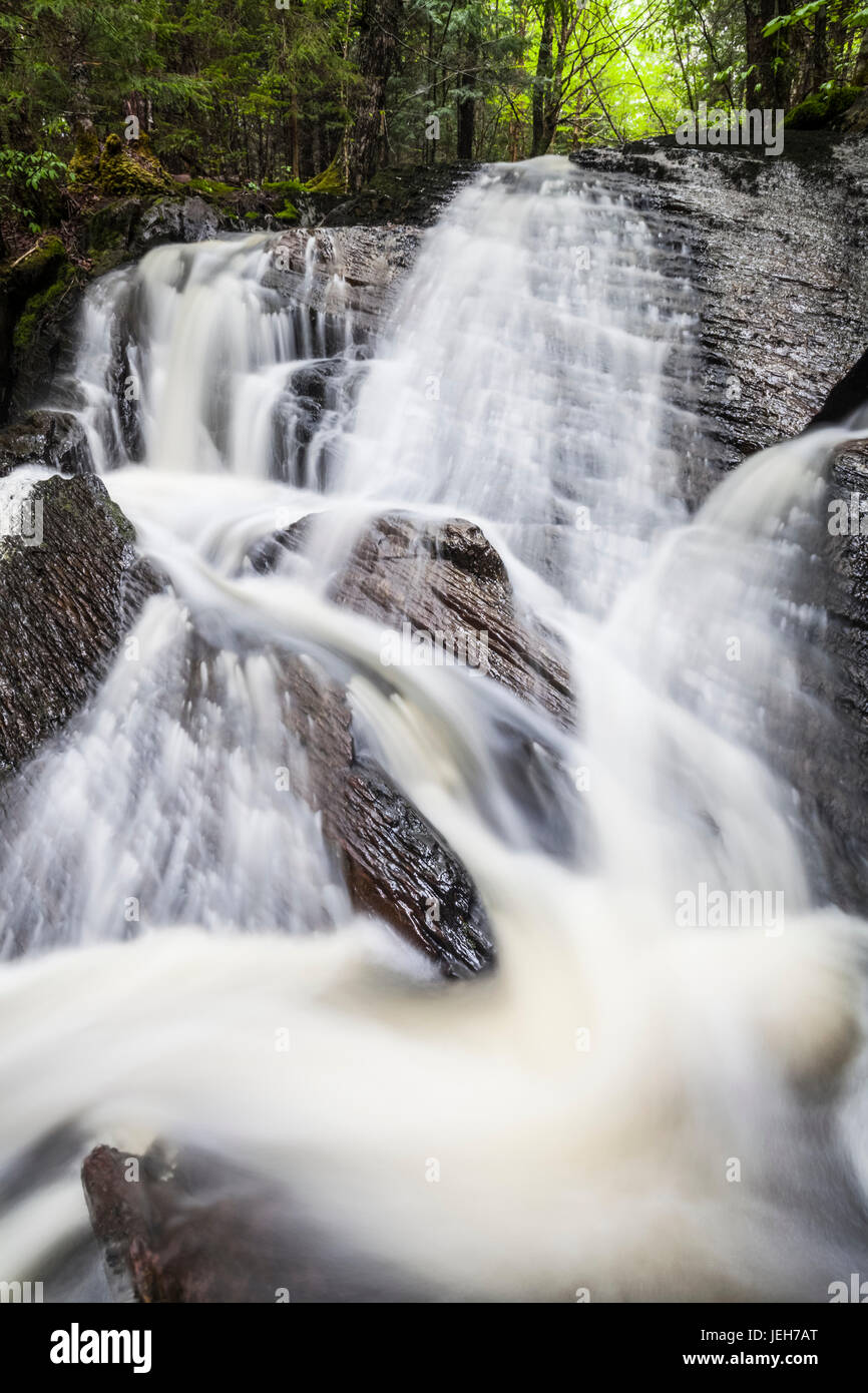 A waterfall splashing down a rocky embankment in a forest; Middle ...