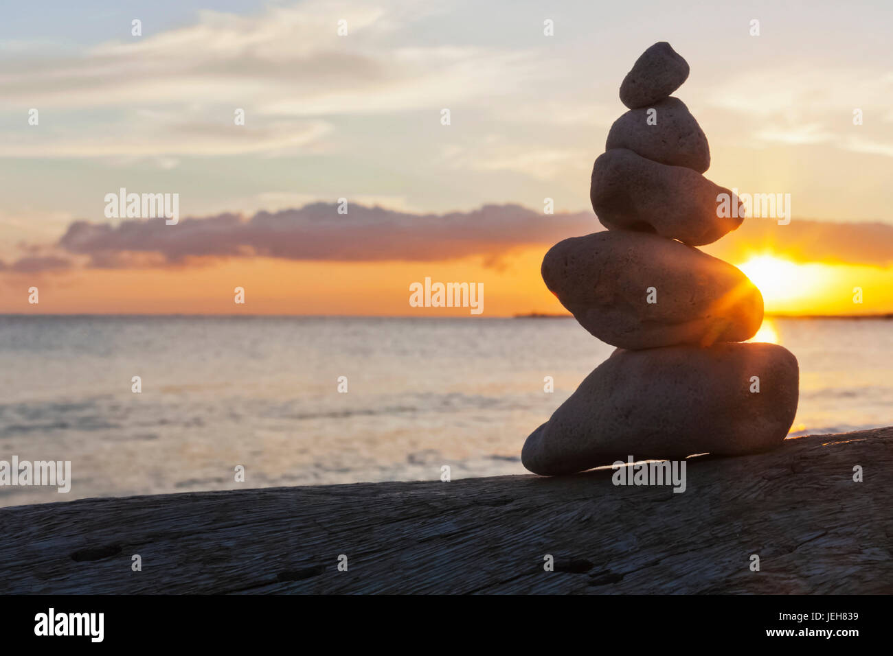A pile of rocks balancing on the sand at the water's edge with the ...