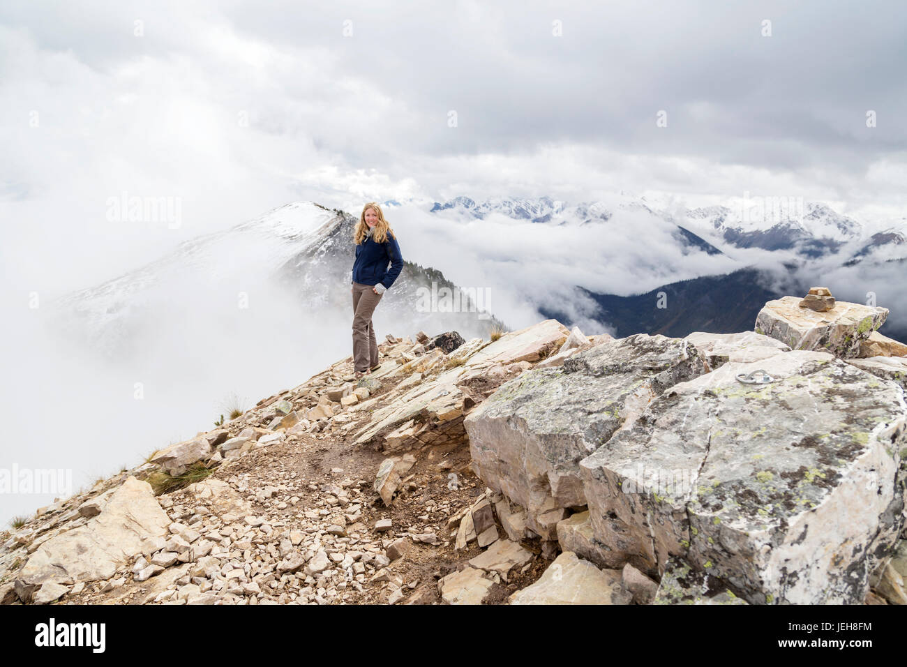 A female hiker reaches the mountain summit and poses for a photo of the ...