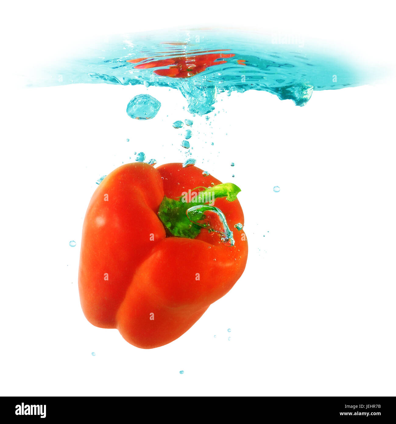 sweet pepper falling into the water isolated on a white background ...
