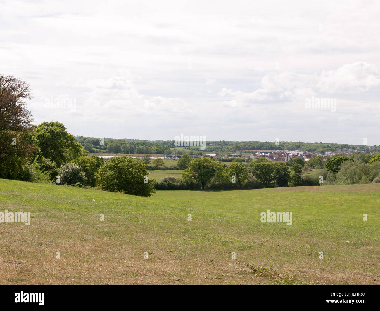 a big open field of grass with trees and river in the distance on a ...