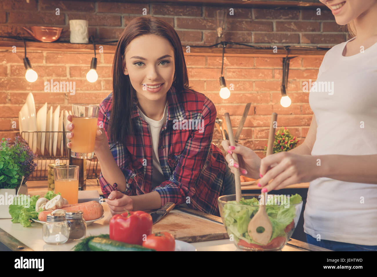 Young female friends cooking meal together at home mixing salad Stock ...
