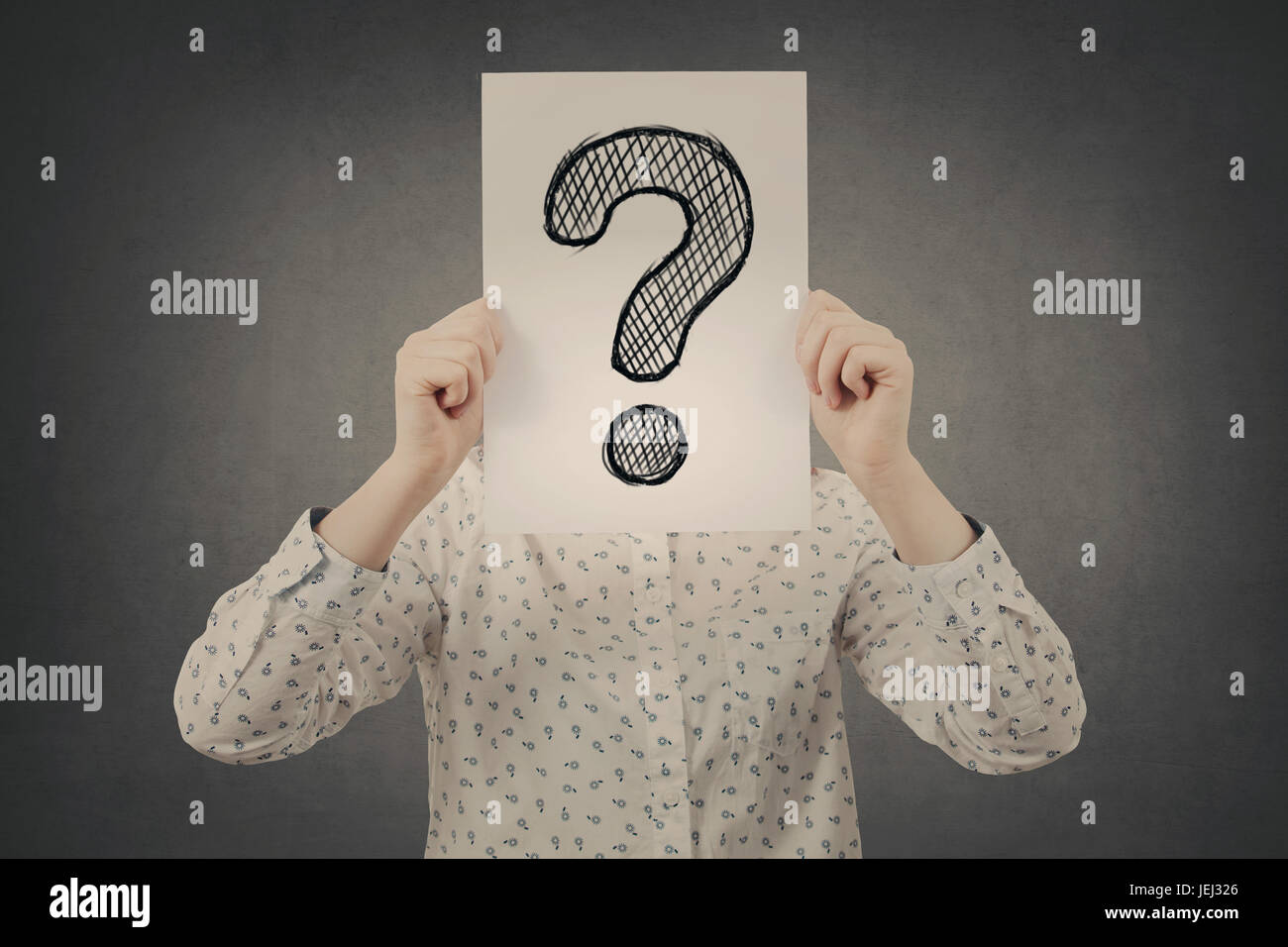 Businesswoman covering his face using a white paper with drawn question ...