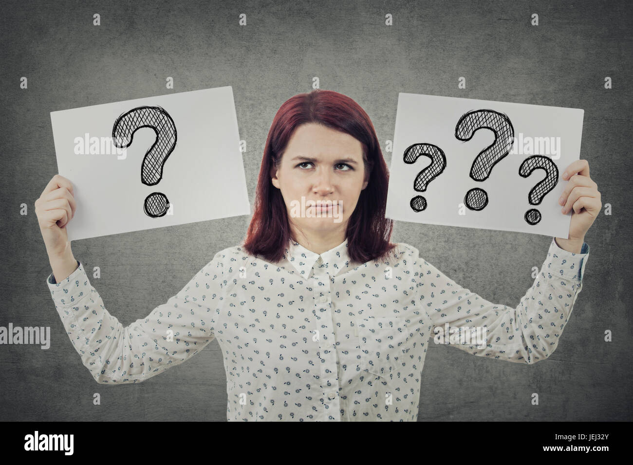 Confused young woman holding two white papers in hands, isolated on ...