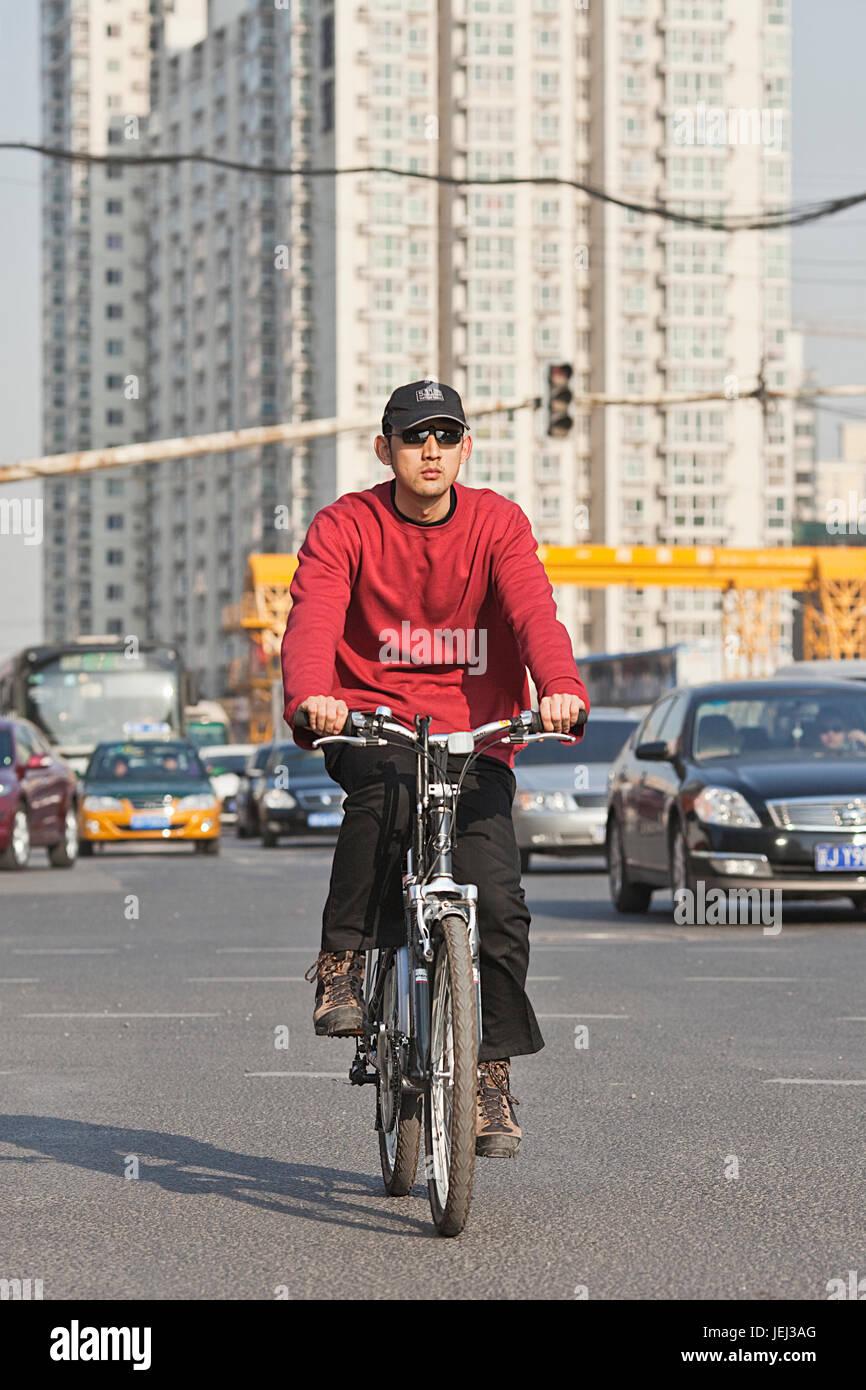 BEIJING–MARCH 27, 2012. Man cycles in Beijing downtown. Increasingly ...