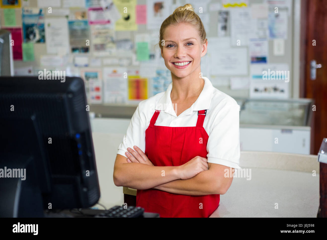 Smiling shop assistant with arms crossed Stock Photo - Alamy