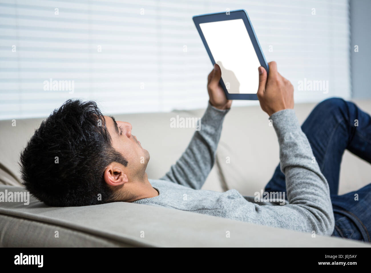 Handsome man using tablet on the sofa Stock Photo - Alamy
