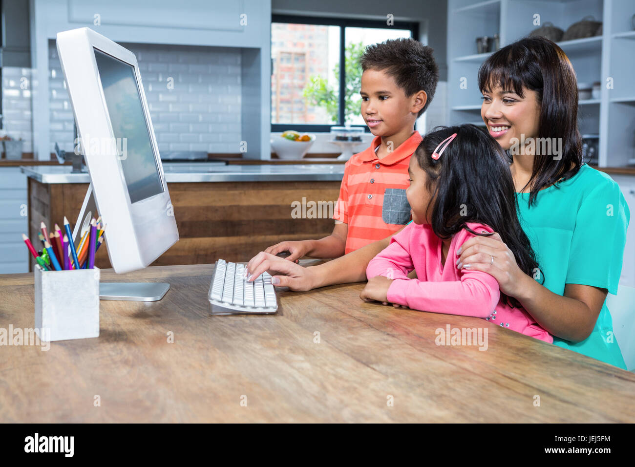 Happy mother using computer with her children Stock Photo - Alamy
