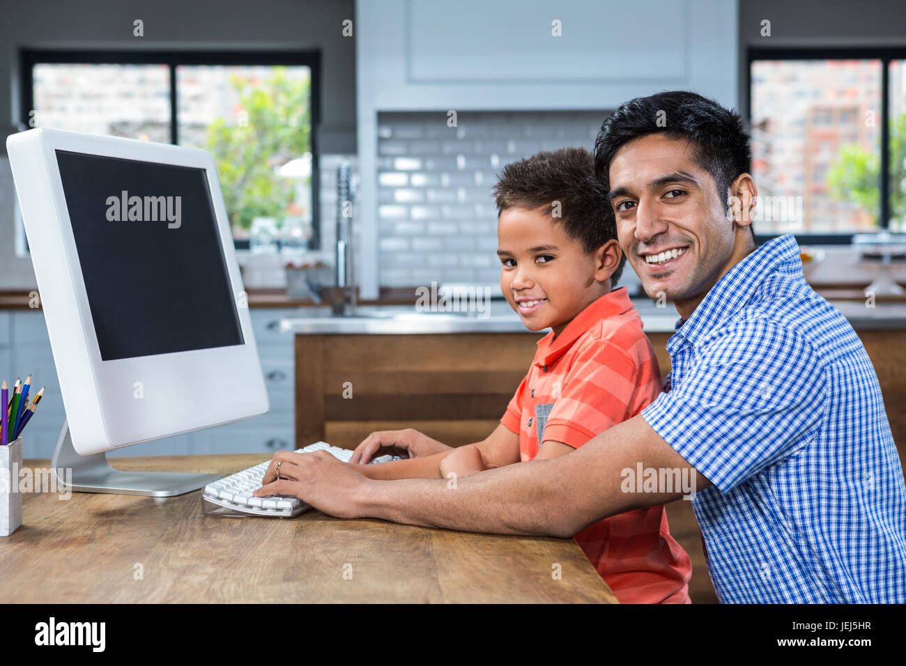 Smiling father using computer with his son Stock Photo - Alamy