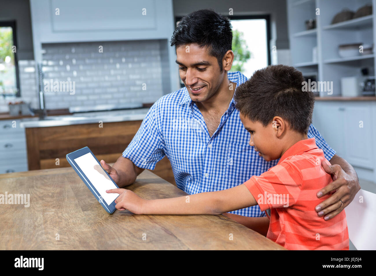 Smiling father using tablet with his son Stock Photo - Alamy