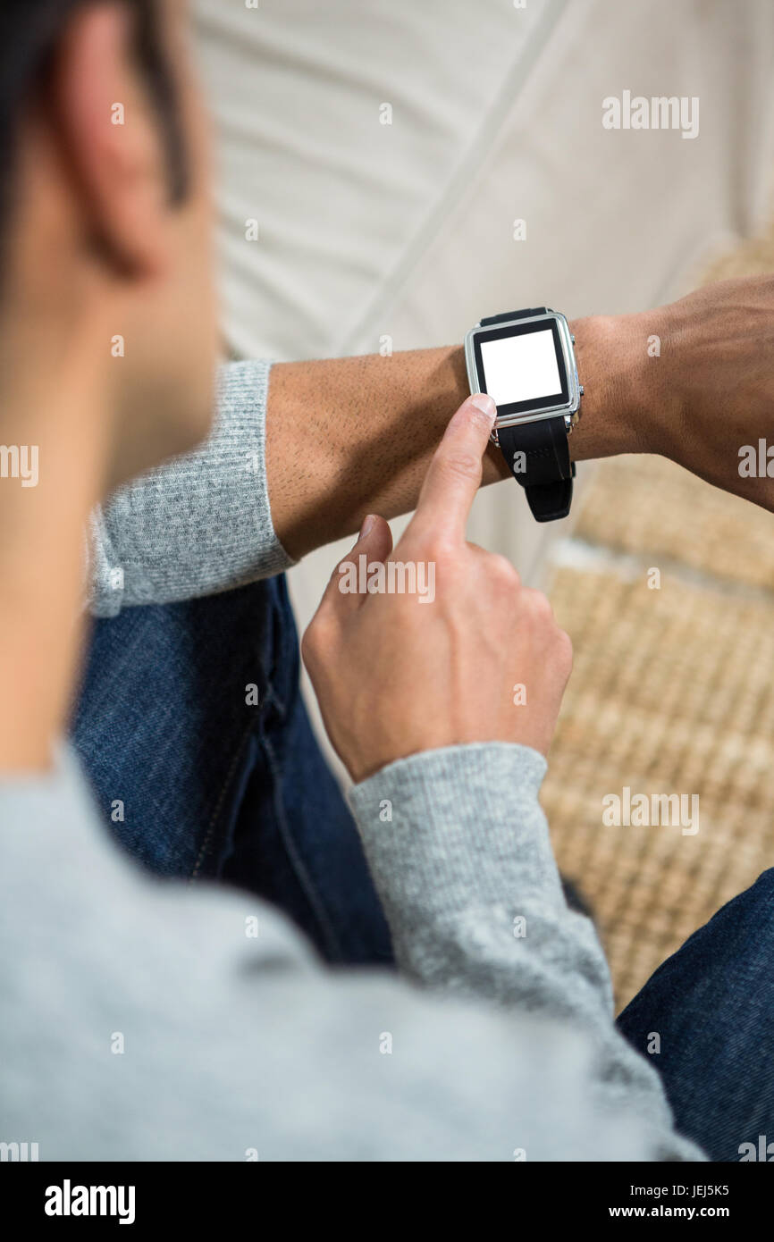 Handsome man using smartwatch on the sofa Stock Photo - Alamy