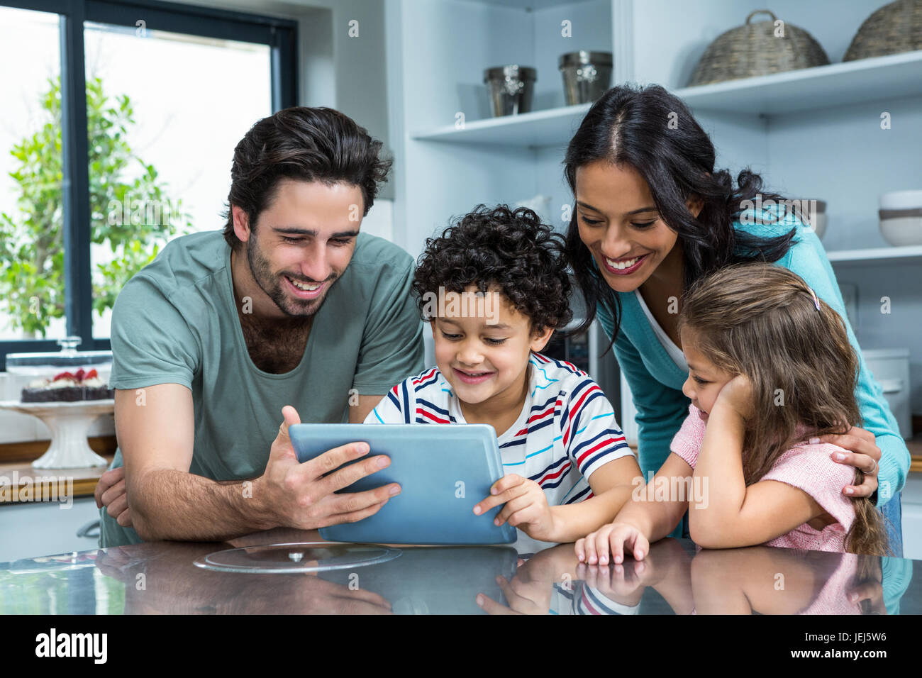 Happy family using tablet in kitchen Stock Photo - Alamy