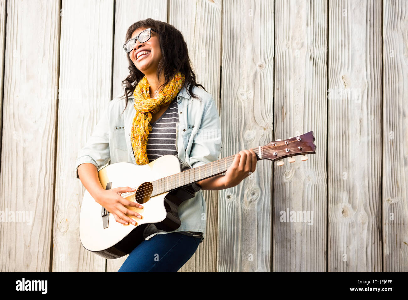 Smiling casual woman playing guitar Stock Photo - Alamy