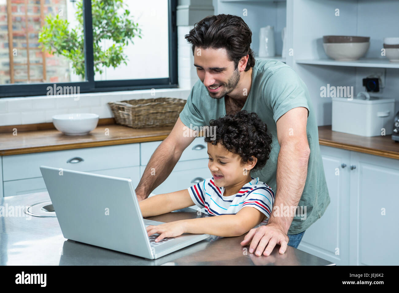 Smiling father using laptop with his son Stock Photo - Alamy